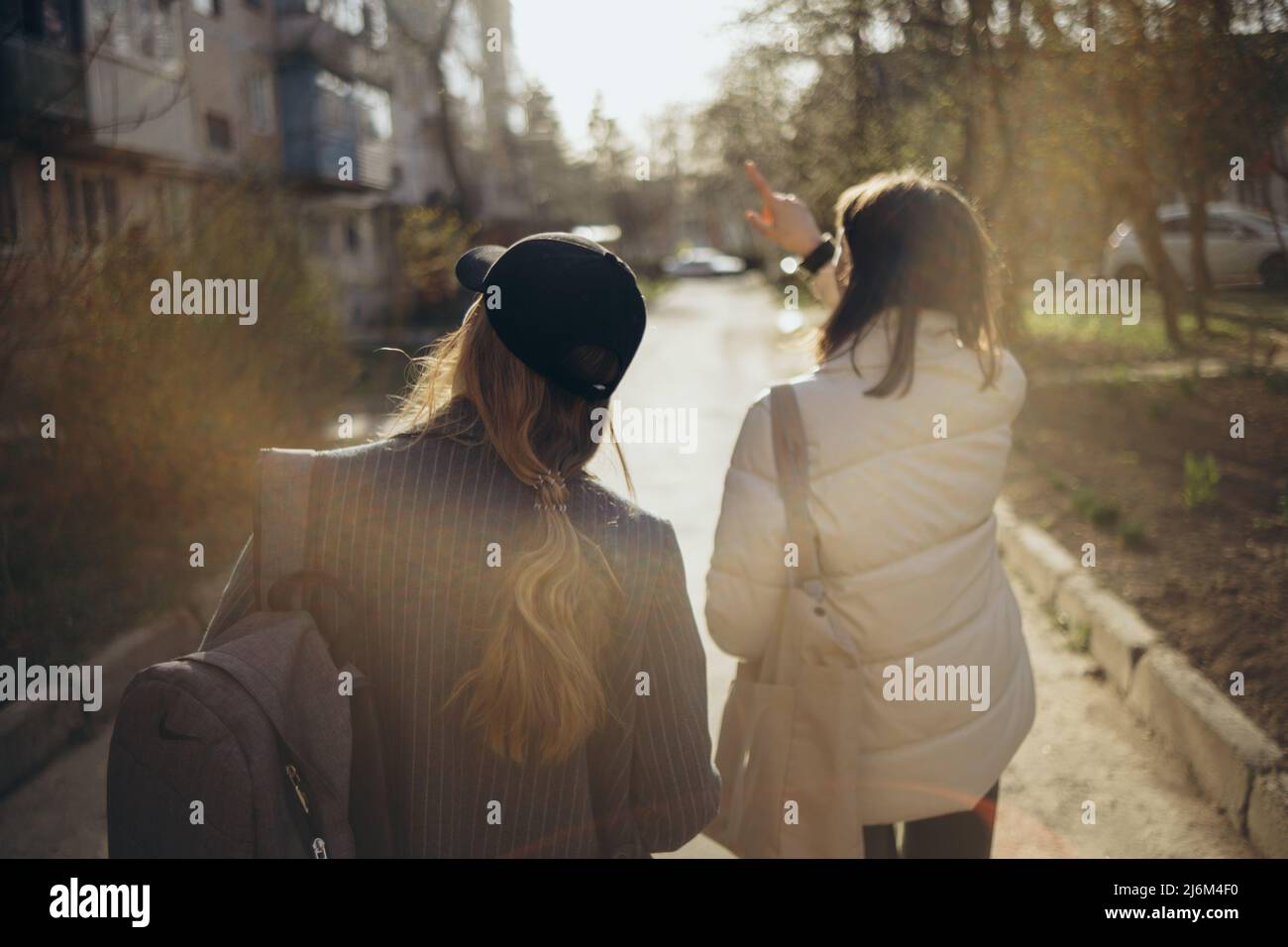Back view portrait of two women walking and talking in a park asunny ...