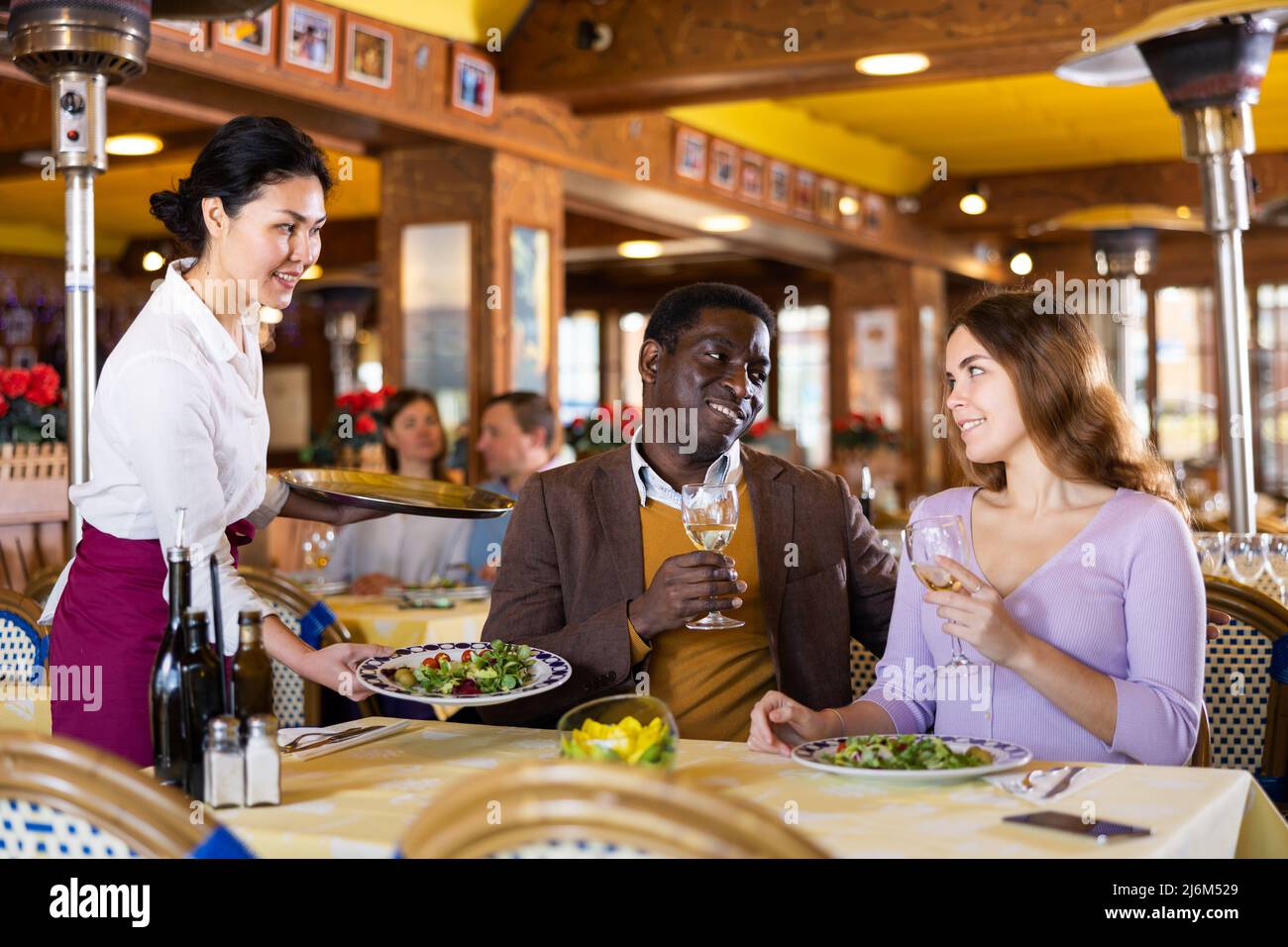 Waitress serving table for couple in restaurant Stock Photo - Alamy