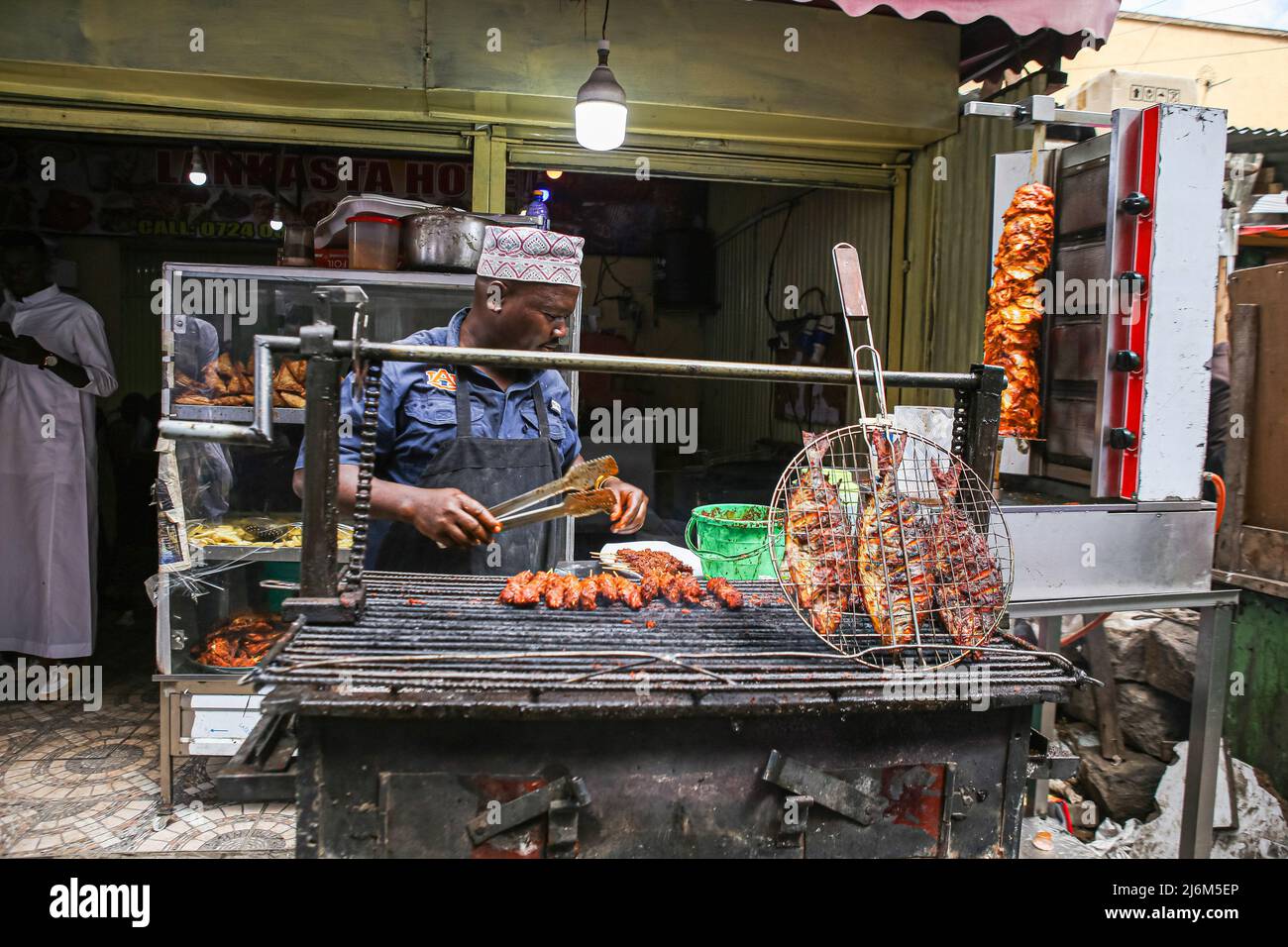 Kenyan chef prepares meat skewers, grilled fish, and shawarma as he ...