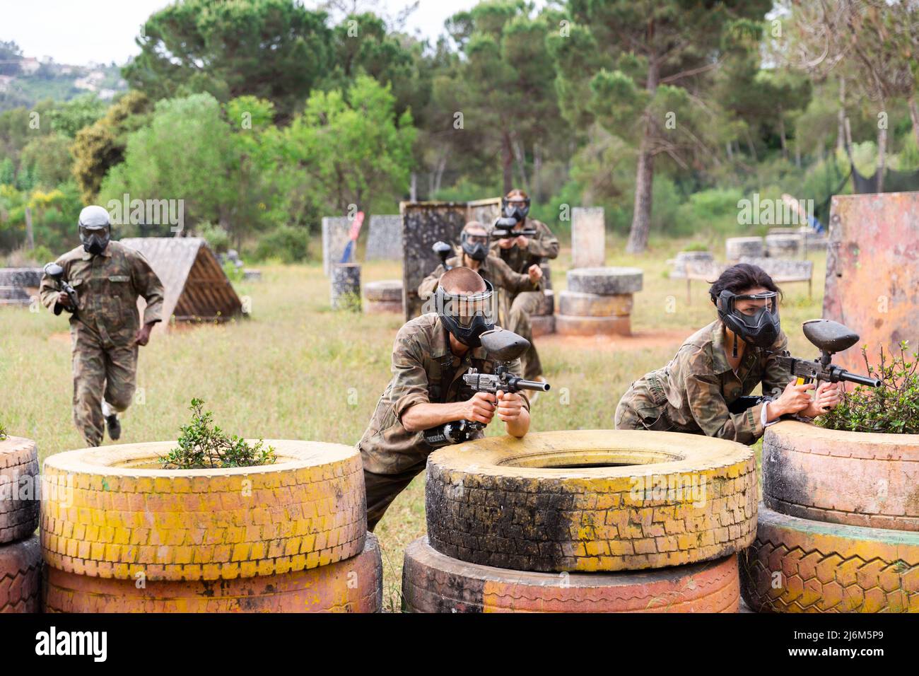 Expressive paintball team running with a marker guns at open playing ...