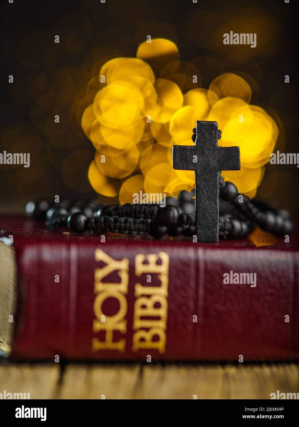 Macro shot. Crucifixion on a rosary on a book - the Holy Bible. Yellow ...