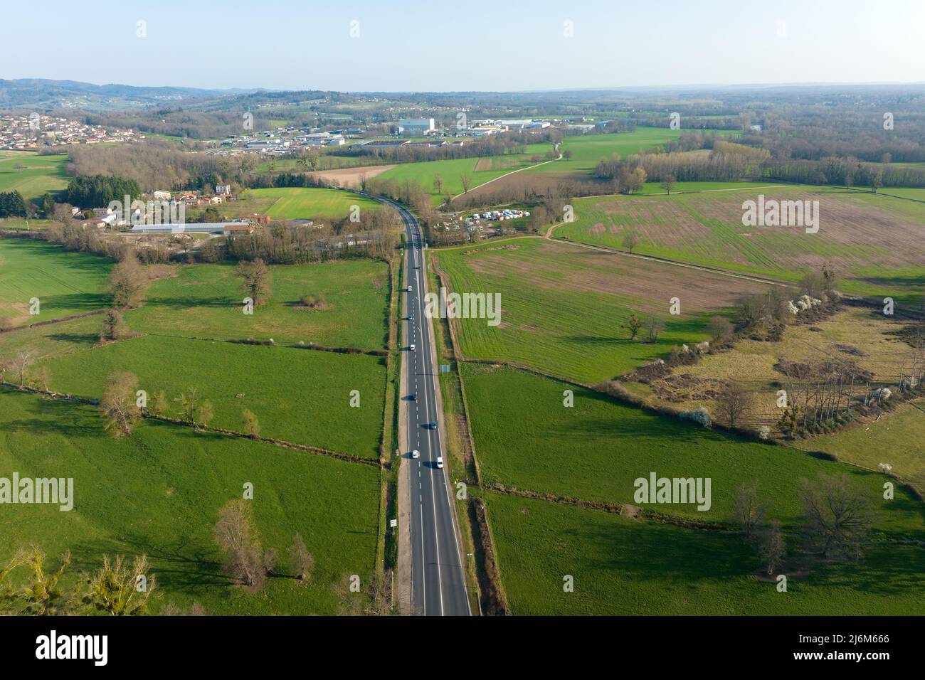 Aerial view of intercity road between green agricultural fields with ...