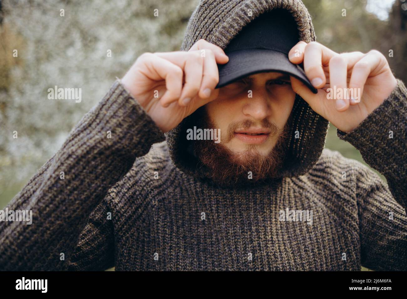 Headshot of a man wearing a brown hooded top with an intense stare at ...