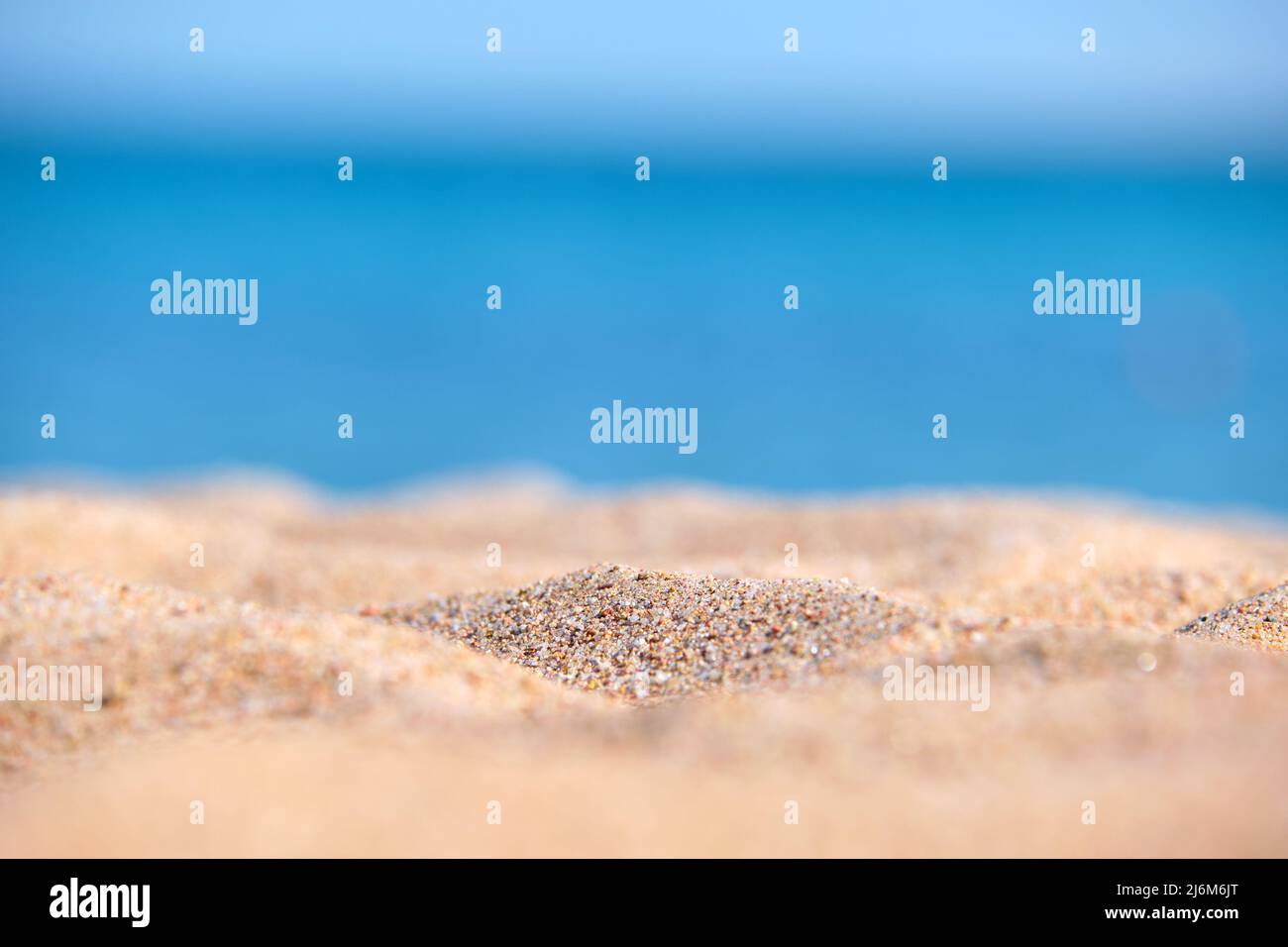 Close up of clean yellow sand surface covering seaside beach with blue ...