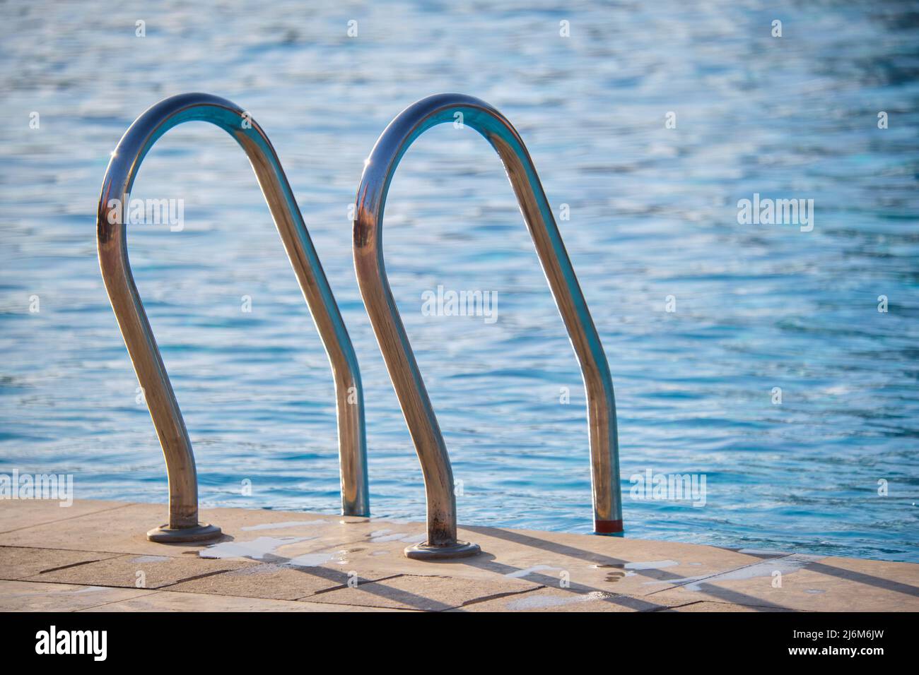 Close up of swimming pool stainless steel handrail descending into ...