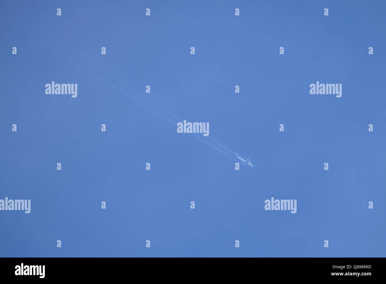 Distant passenger jet plane flying on high altitude on clear blue sky ...