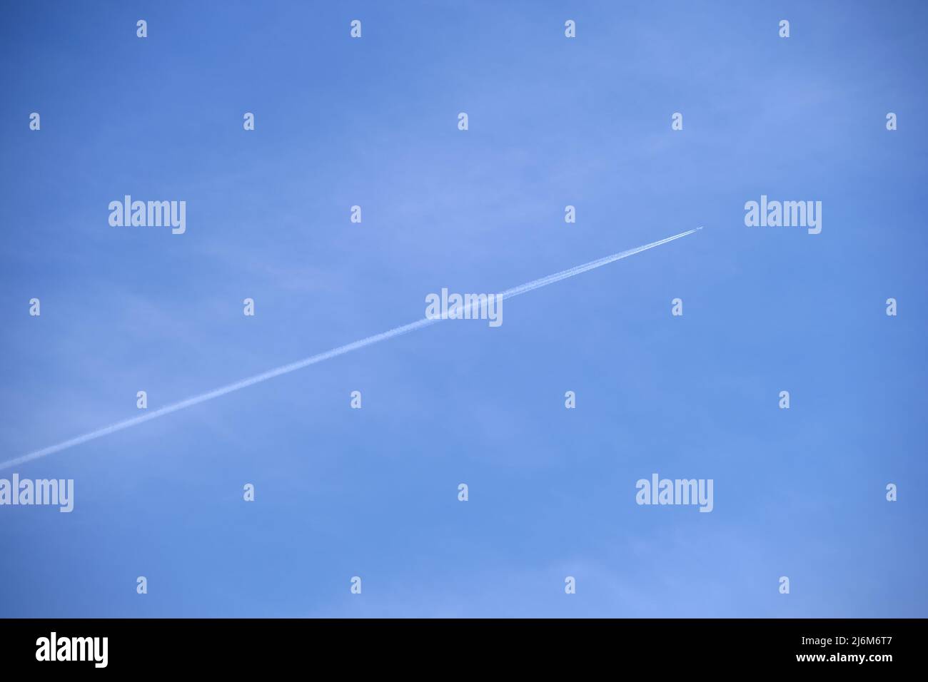 Distant passenger jet plane flying on high altitude on clear blue sky ...