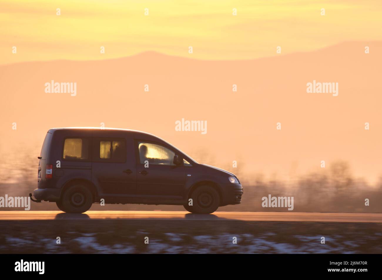 Passenger van driving fast on intercity road at sunset. Highway traffic ...