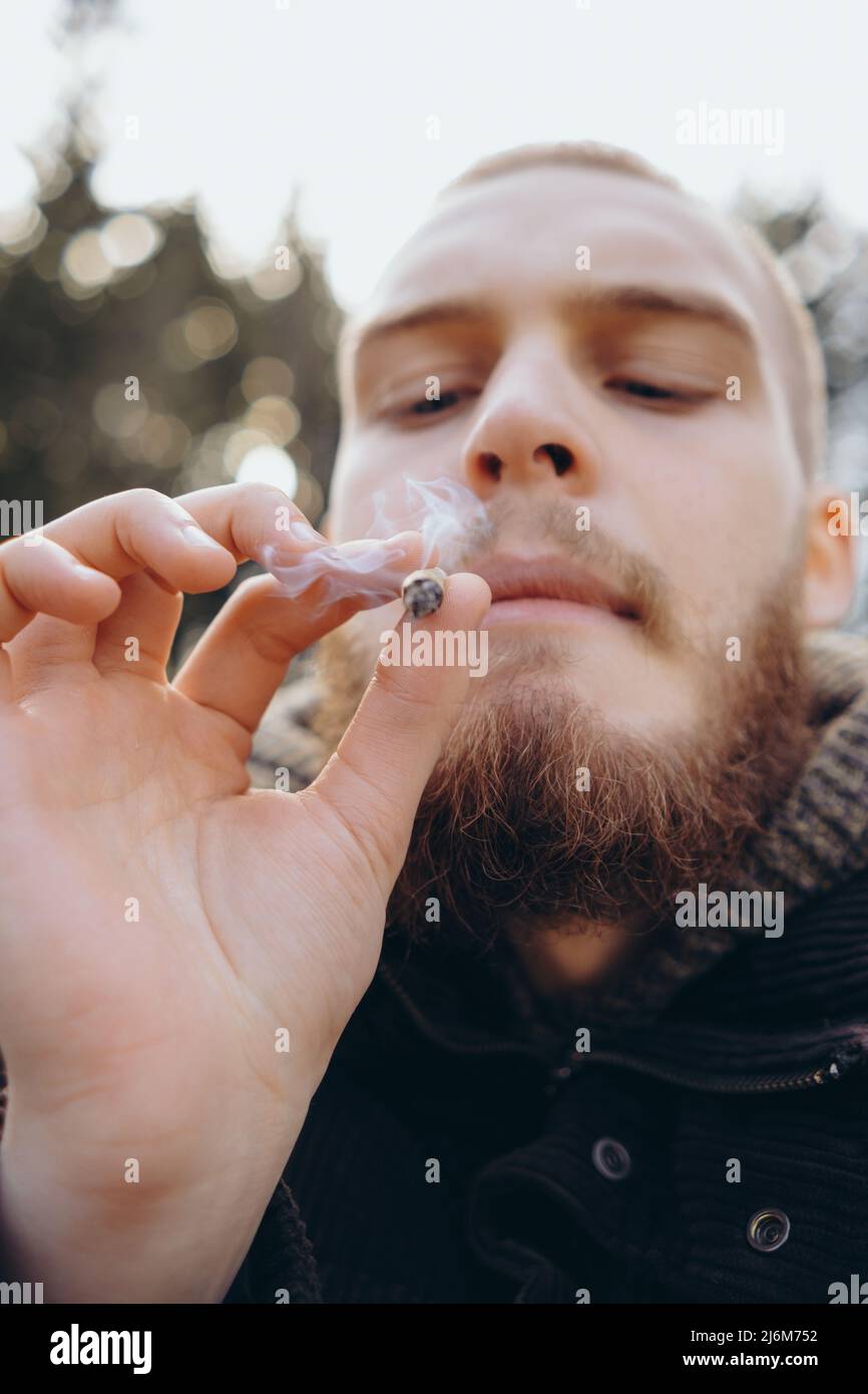 Young man beard smokes cigarette or tobacco. Guy is addicted to ...