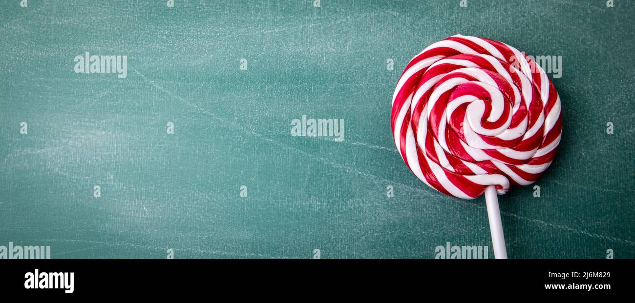 Horizontal banner. Green chalk texture background. Red candy on a stick ...