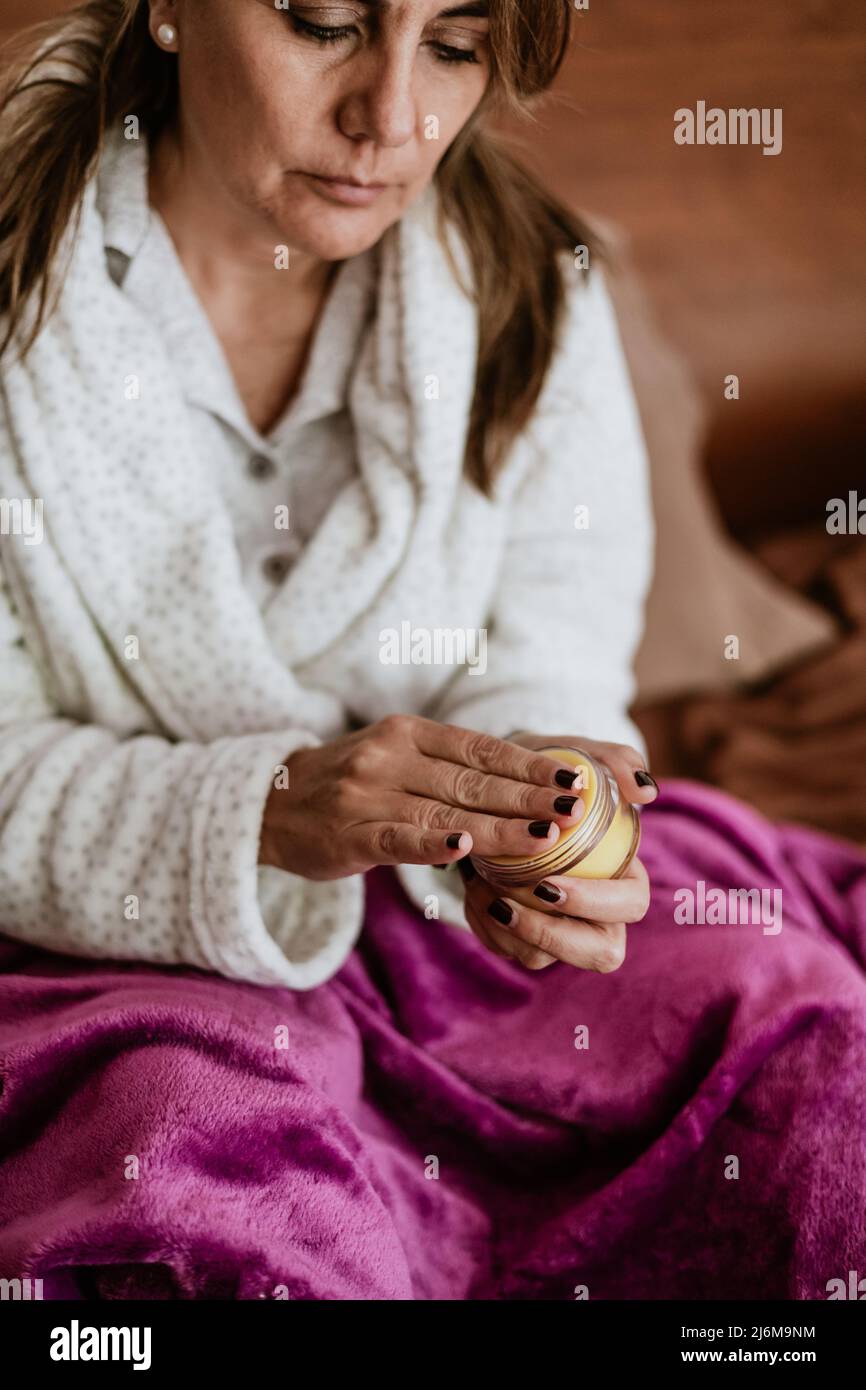 latin ill senior matured woman sneezing and using napkin for flu on bed ...