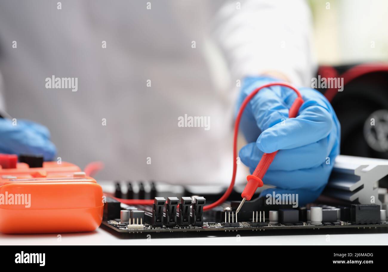 Technician measuring voltage of in computer mainboard using electronic ...