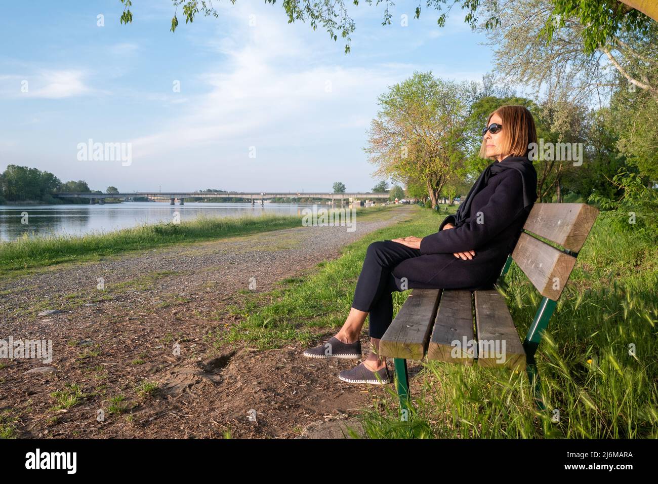 adult mature elegant caucasian woman sitting on a park bench with legs ...
