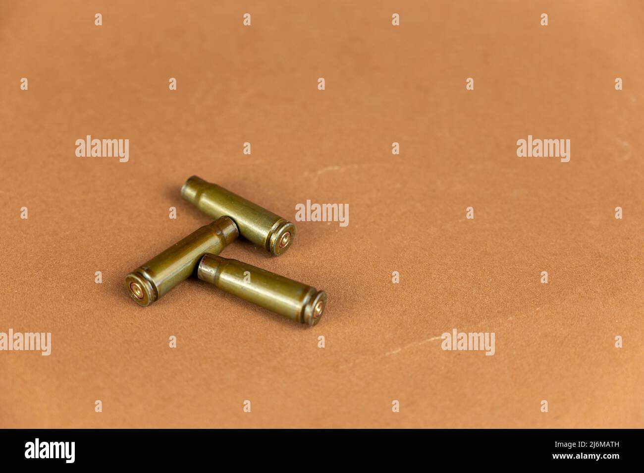 Empty casings against a brown background. Three automatic rifle casings ...