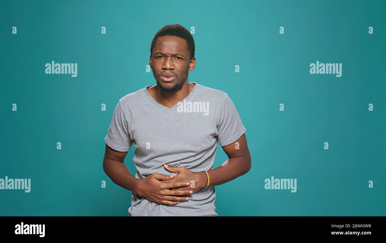 Portrait of male model having stomach ache and abdominal cramp, dealing ...