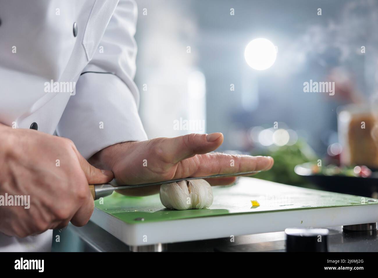 Close up of head cook hands using cooking knife to smash a head of ...