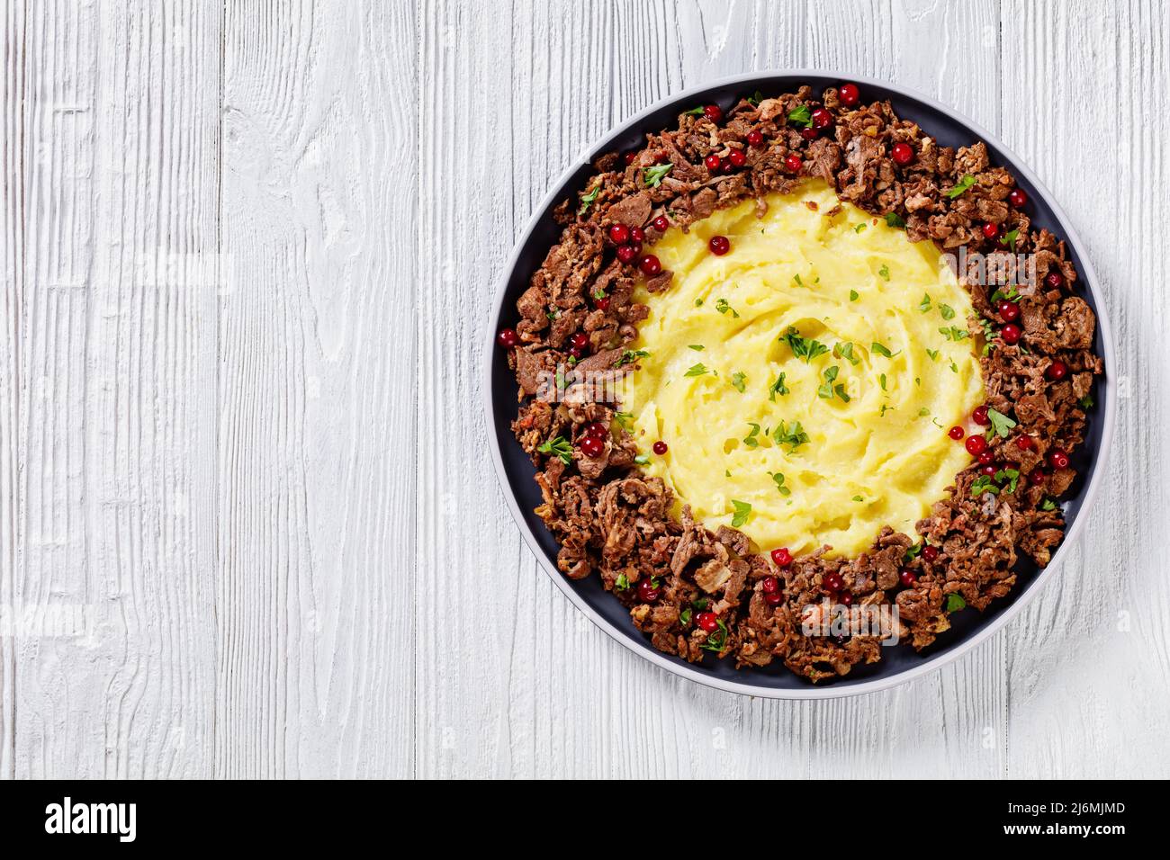 Reindeer Stew with Lingonberries and potato puree on plate on wood ...