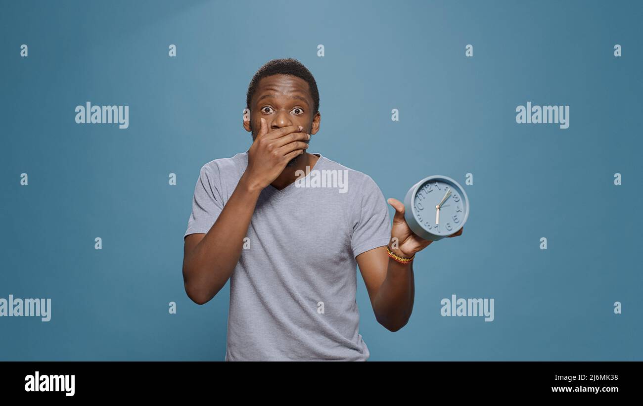 Shocked person looking at wall clock to indicate time, standing over ...
