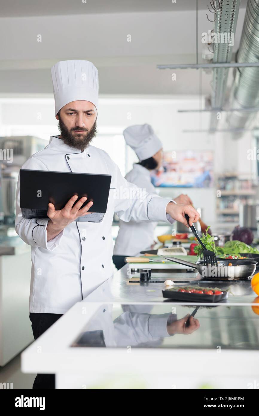 Chef preparing fresh organic vegetable garnish using pan and spatula ...
