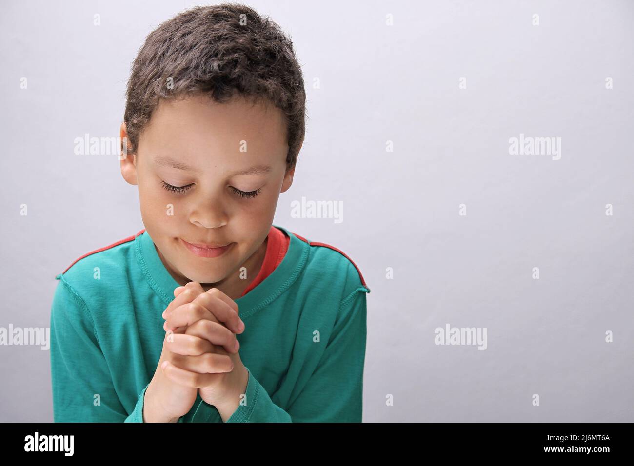 little boy praying to God with hands together with black background ...