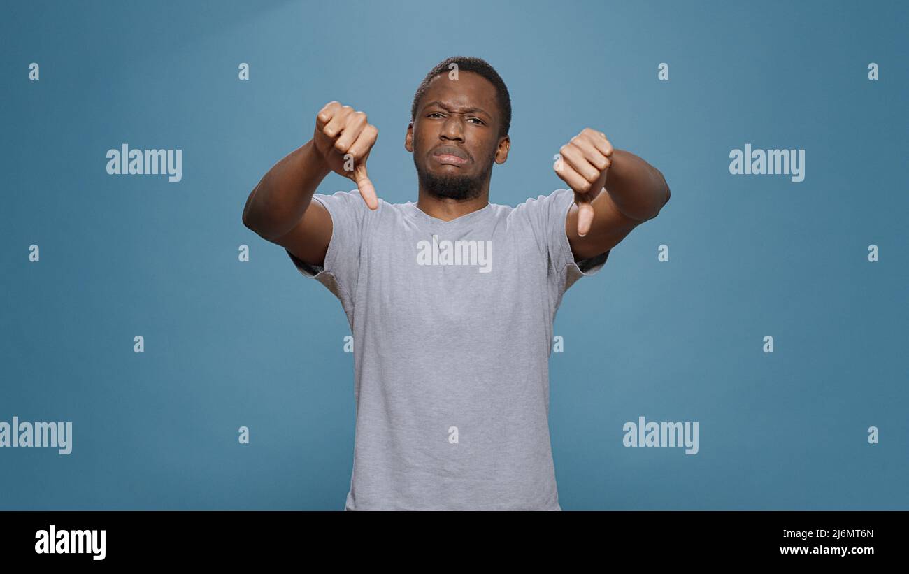 Disappointed person showing thumbs down symbol in studio, doing ...