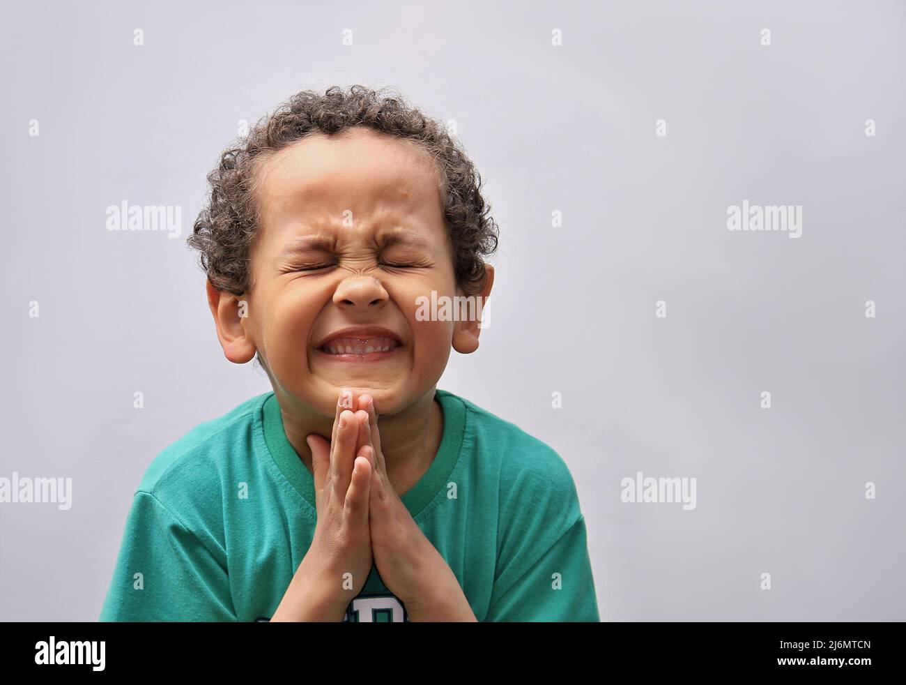 little boy praying to God with hands together with black background ...