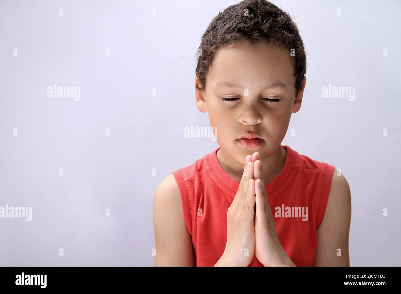 little boy praying to God with hands together with black background ...