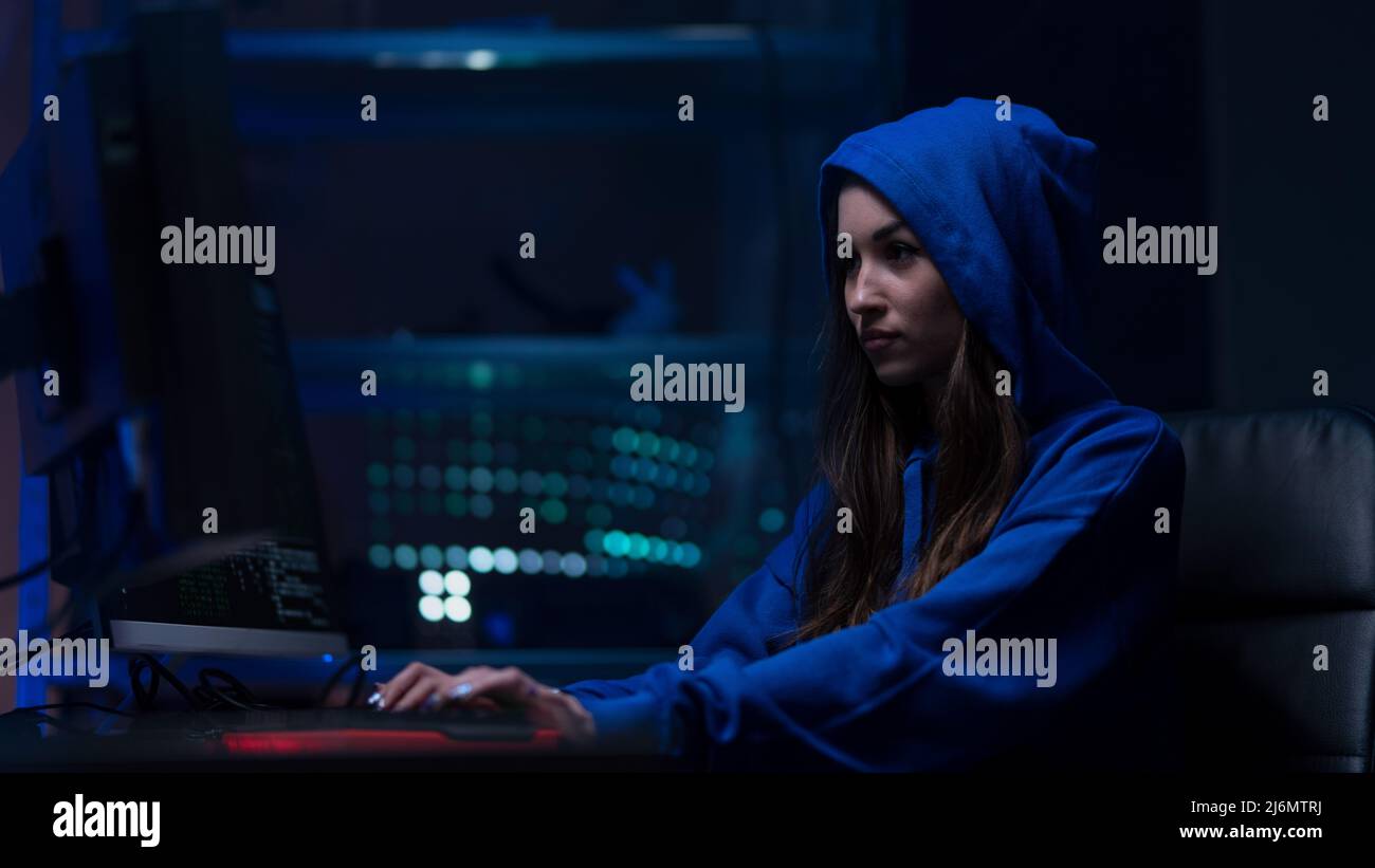 Young woman hacker by computer in the dark room at night, cyberwar ...