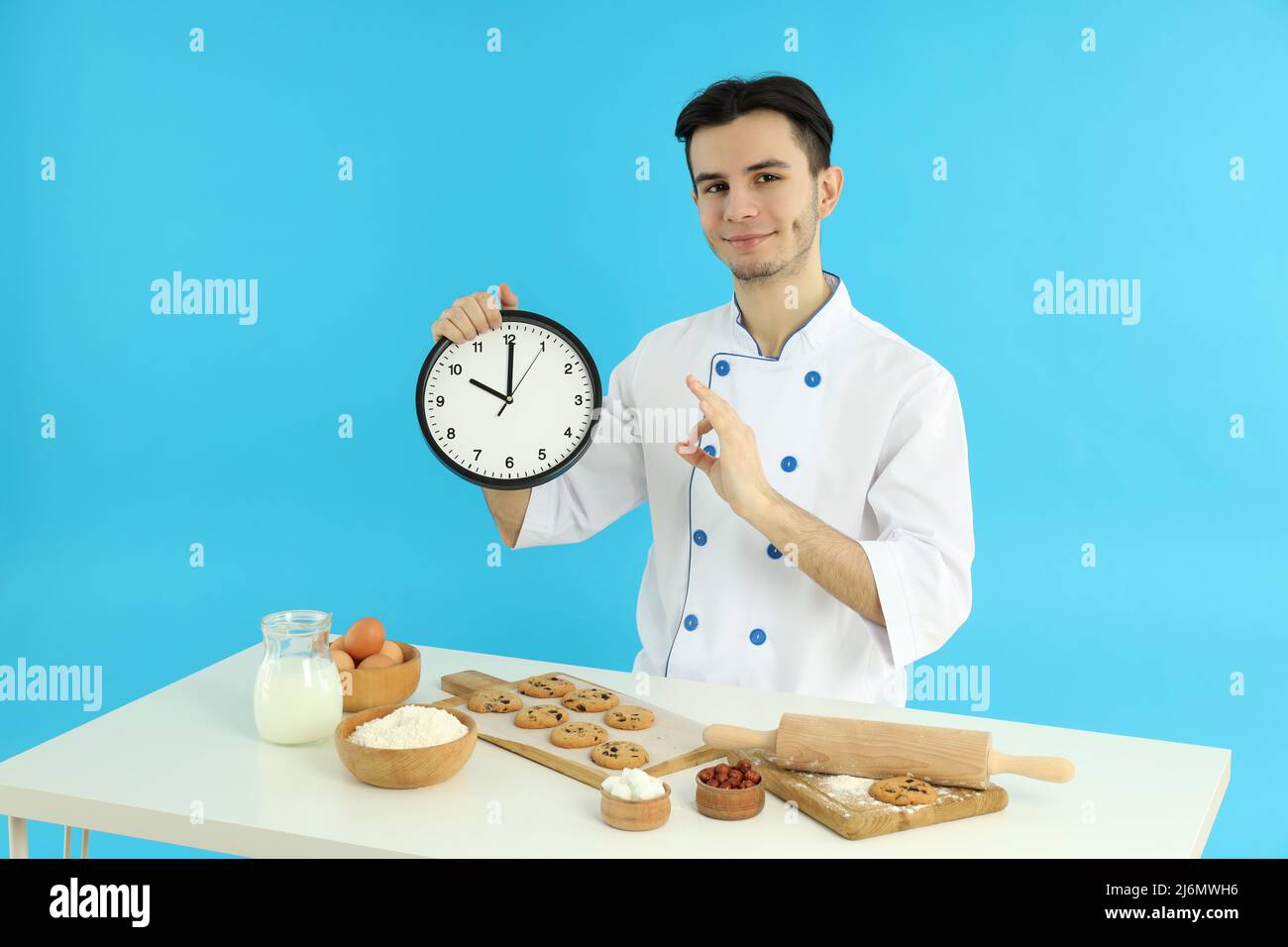 Concept of cooking, young man chef on blue background Stock Photo - Alamy