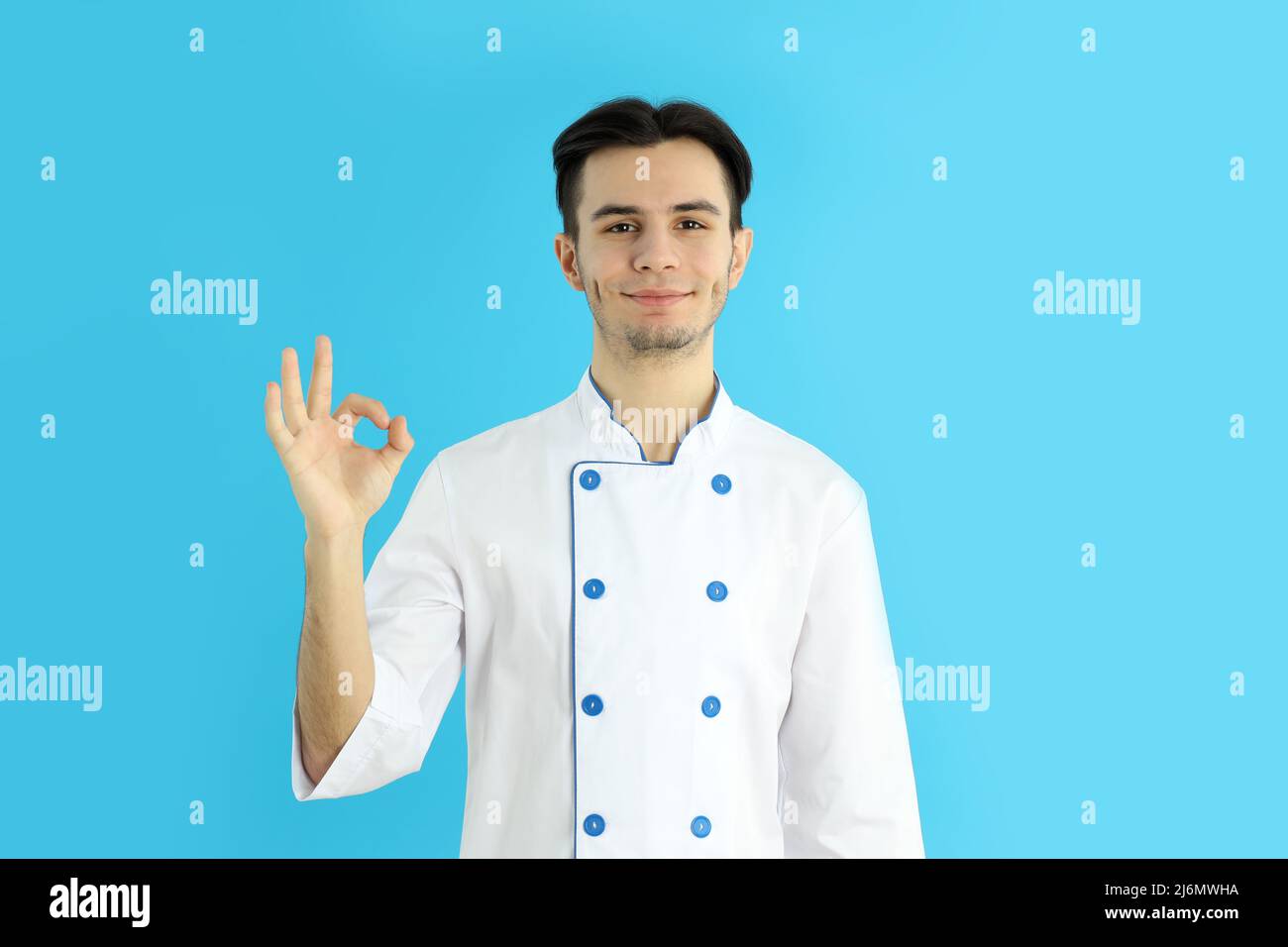 Concept of cooking, young man chef on blue background Stock Photo - Alamy
