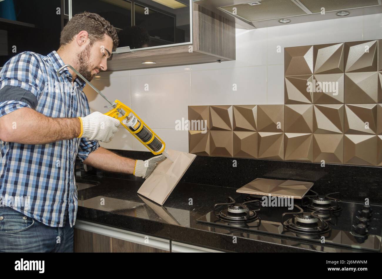 Man renovating, renovating the kitchen, installing tile on the wall ...
