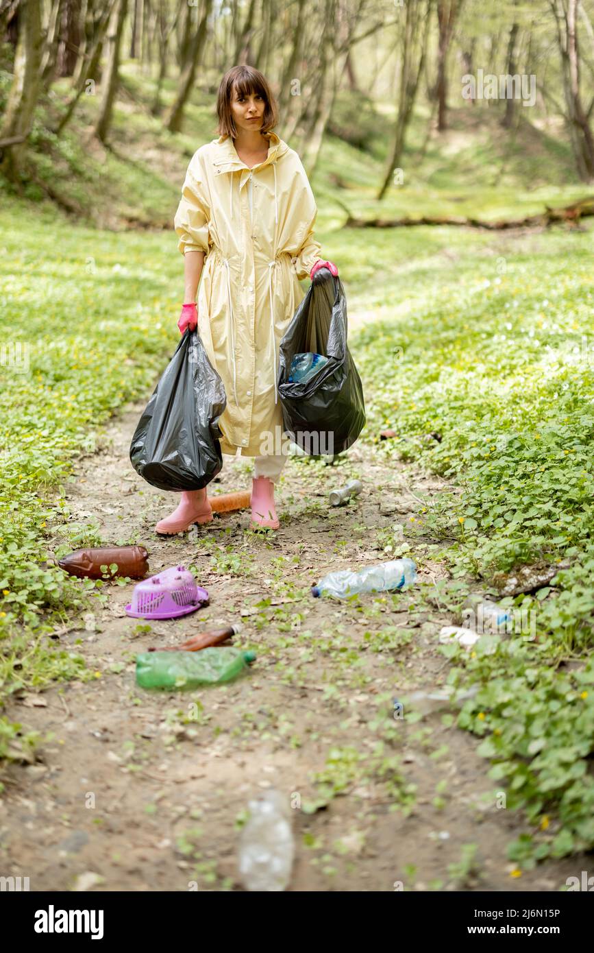 Woman collecting scattered plastic garbage in the woods Stock Photo - Alamy