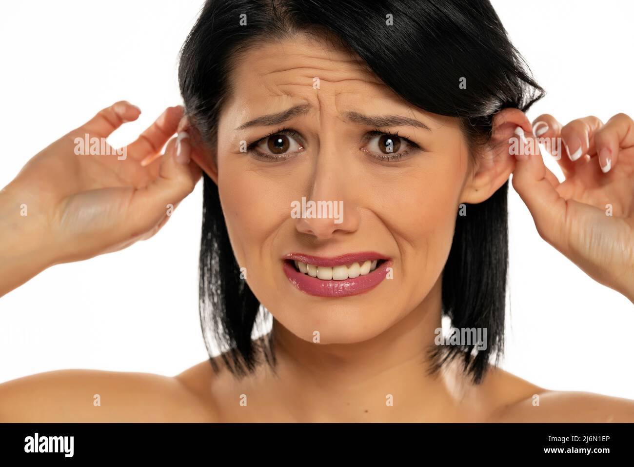 Beautiful young woman pulling her ears with her fingers on white ...