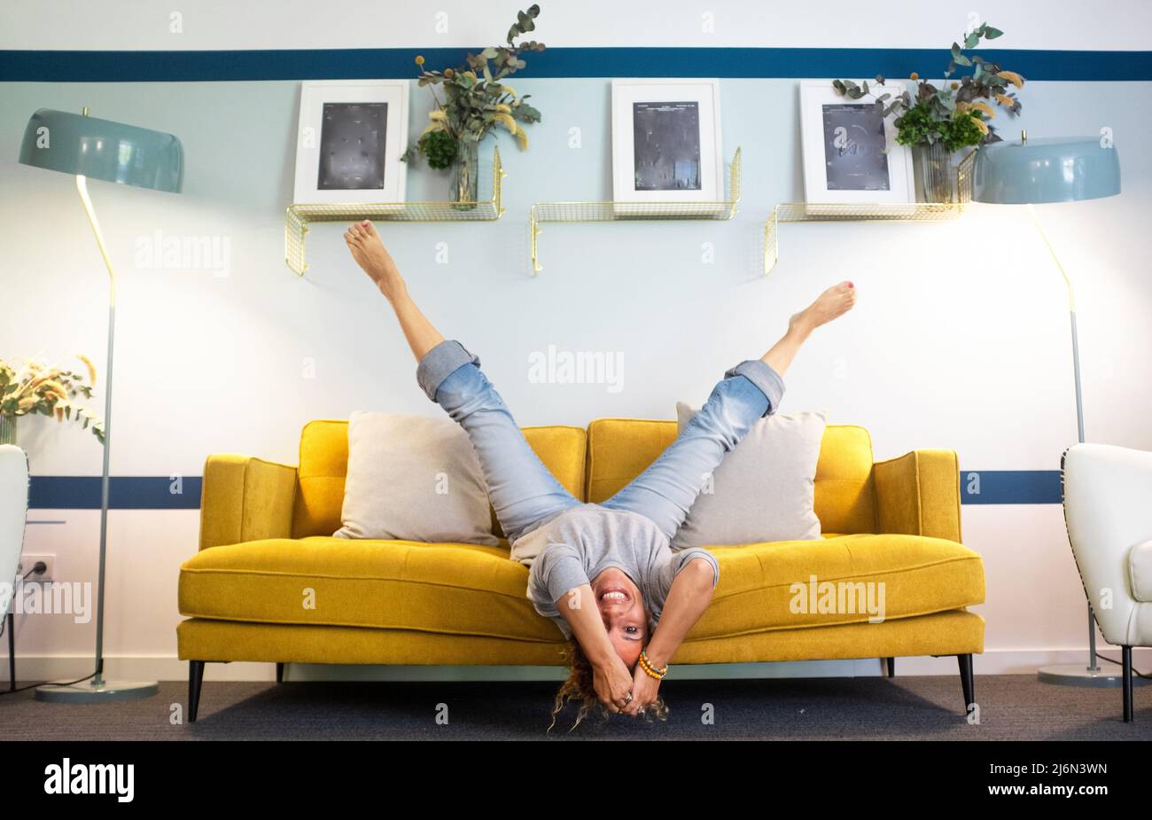 Happy And Joyful Adult Woman Lay Down On The Sofa In Reverse Position