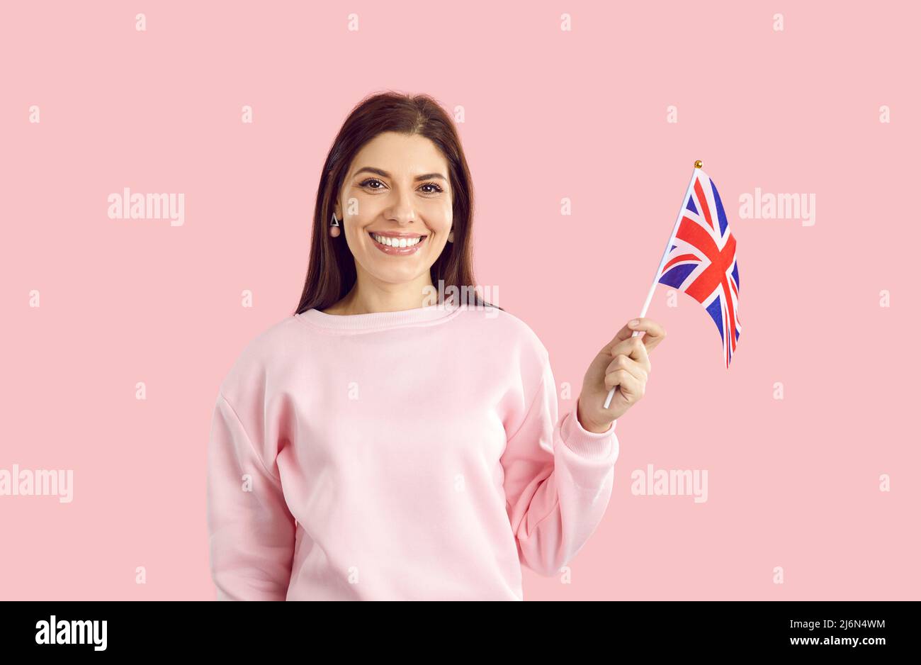Happy young English woman isolated on pink background holding flag of ...