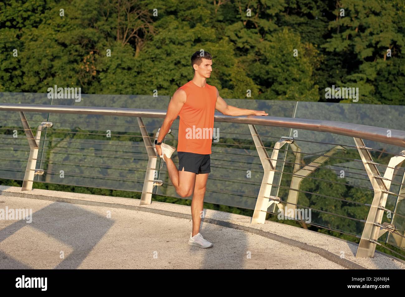 Athletic guy in sportswear grab ankle with hand stretching leg after ...