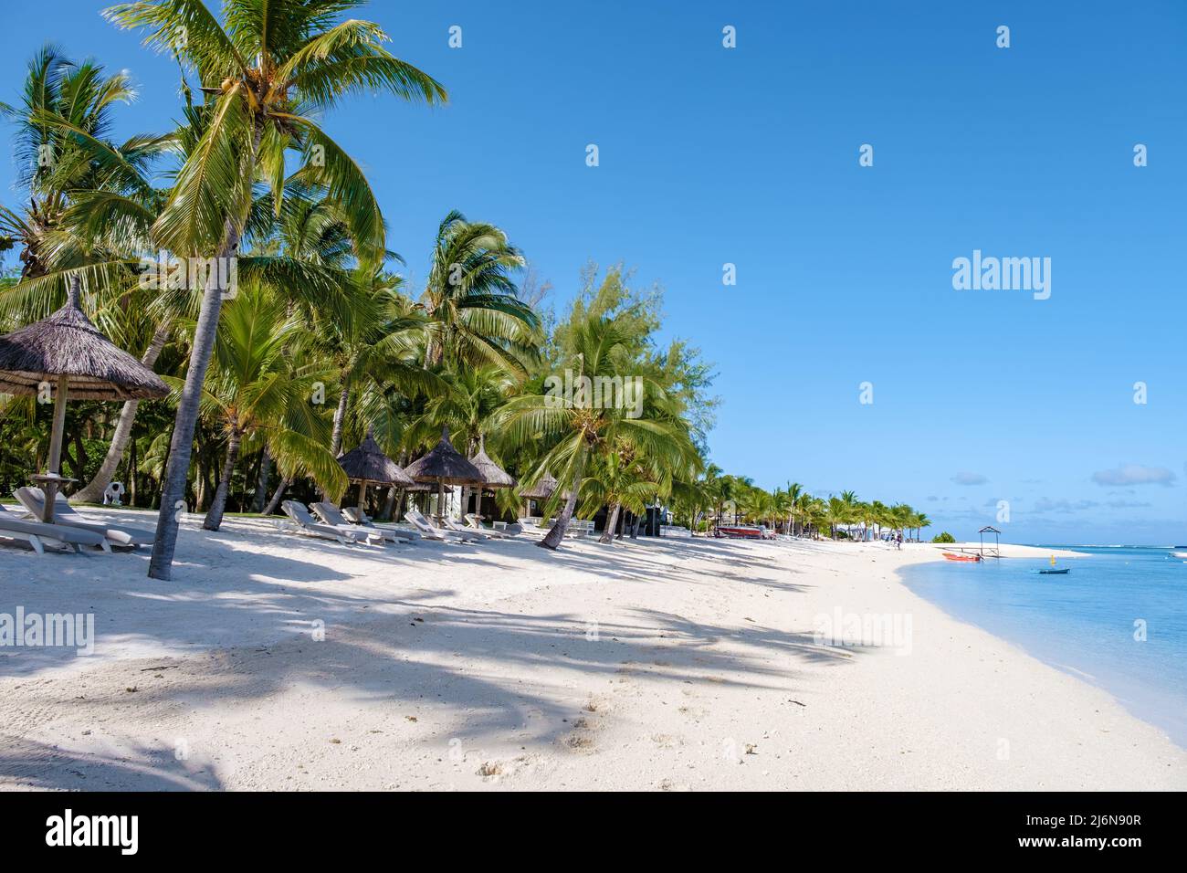 Tropical beach with palm trees and white sand blue ocean and beach beds ...