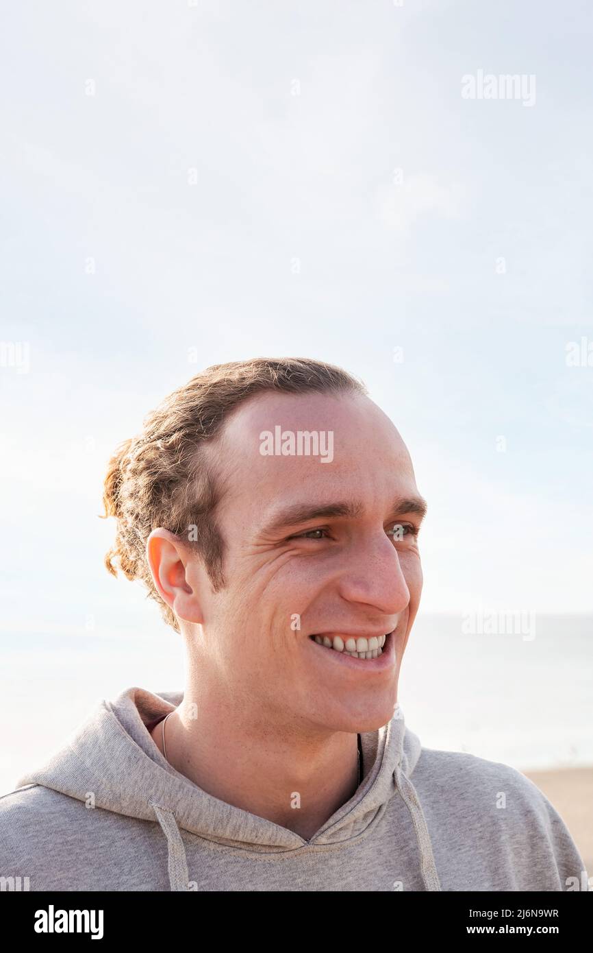 vertical portrait of a young caucasian man smiling happy with the sky ...