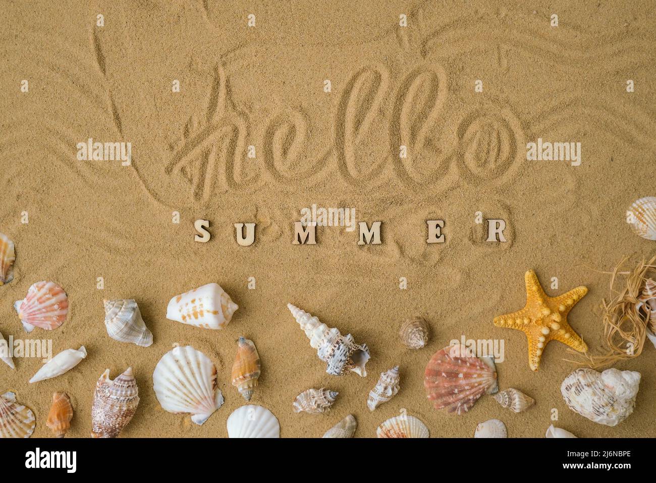 Composition with text HELLO SUMMER seashells, pebbles, mockup on sand ...