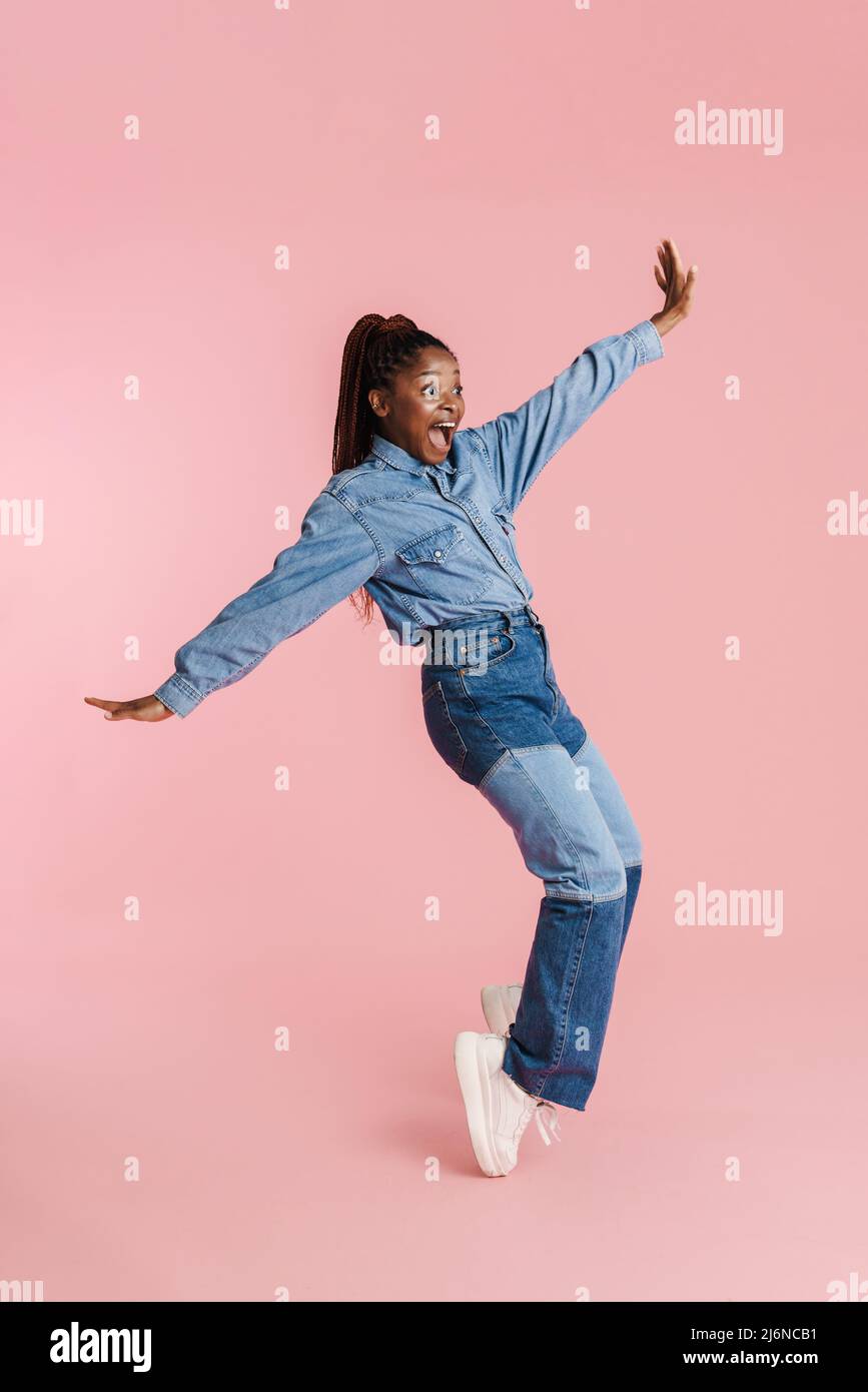 Young black woman wearing denim clothes dancing at camera isolated over ...
