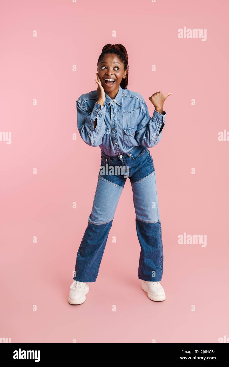 Young black woman screaming and pointing finger aside isolated over ...