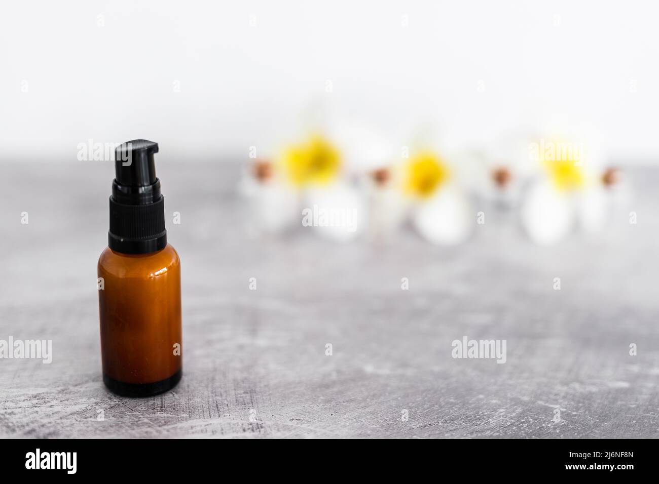 amber skincare bottle with flowers in the background, concept of ...