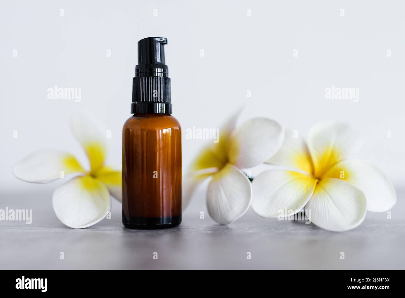 amber skincare bottle with flowers in the background, concept of ...