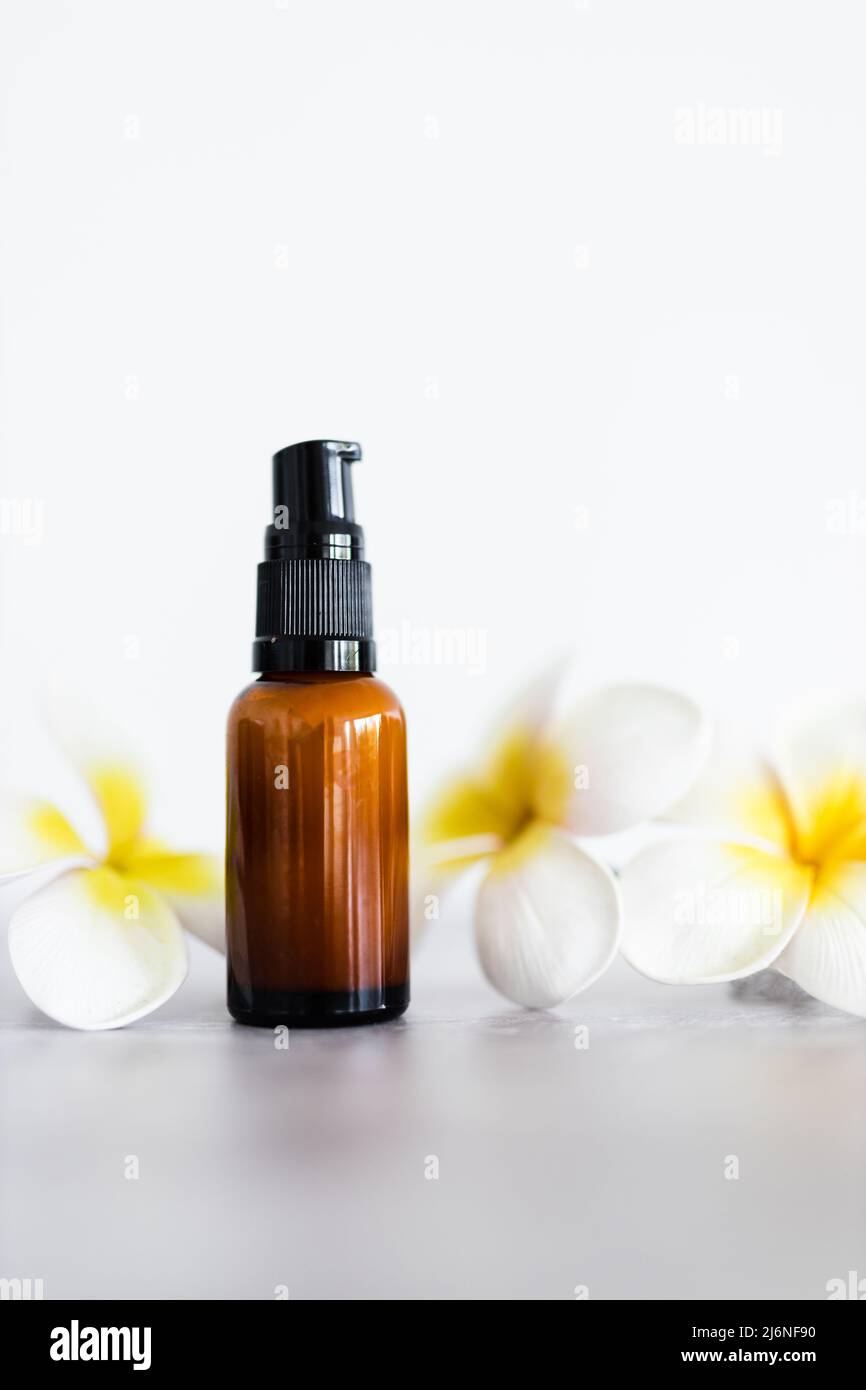 amber skincare bottle with flowers in the background, concept of ...