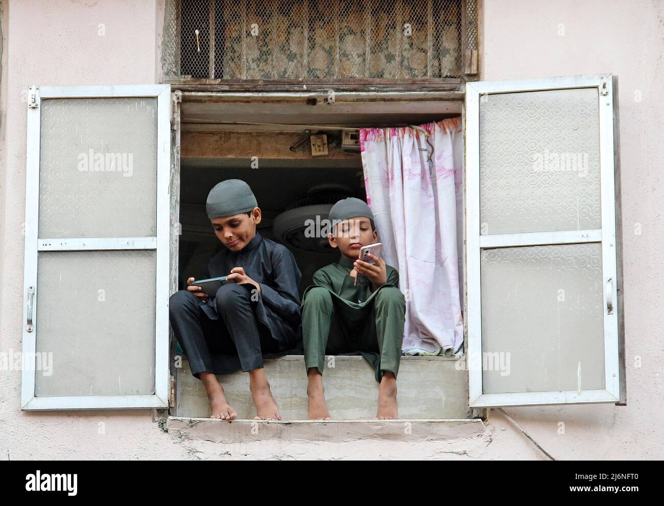 Muslim boys seen using mobile phones as they sit on the balcony of ...