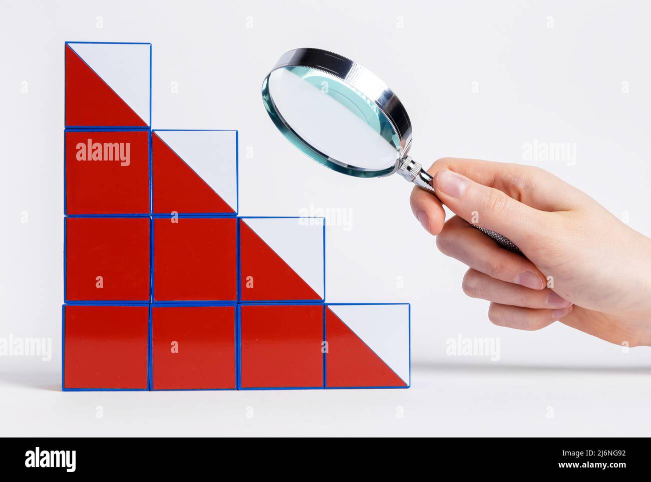 Hand with magnifying glass over falling chart from cubes. Analysis of ...