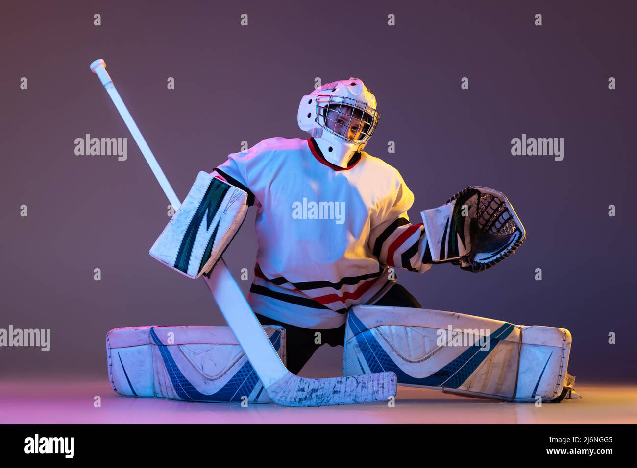 Portrait of teen boy, hockey player, goalkeeper catching puck with ...
