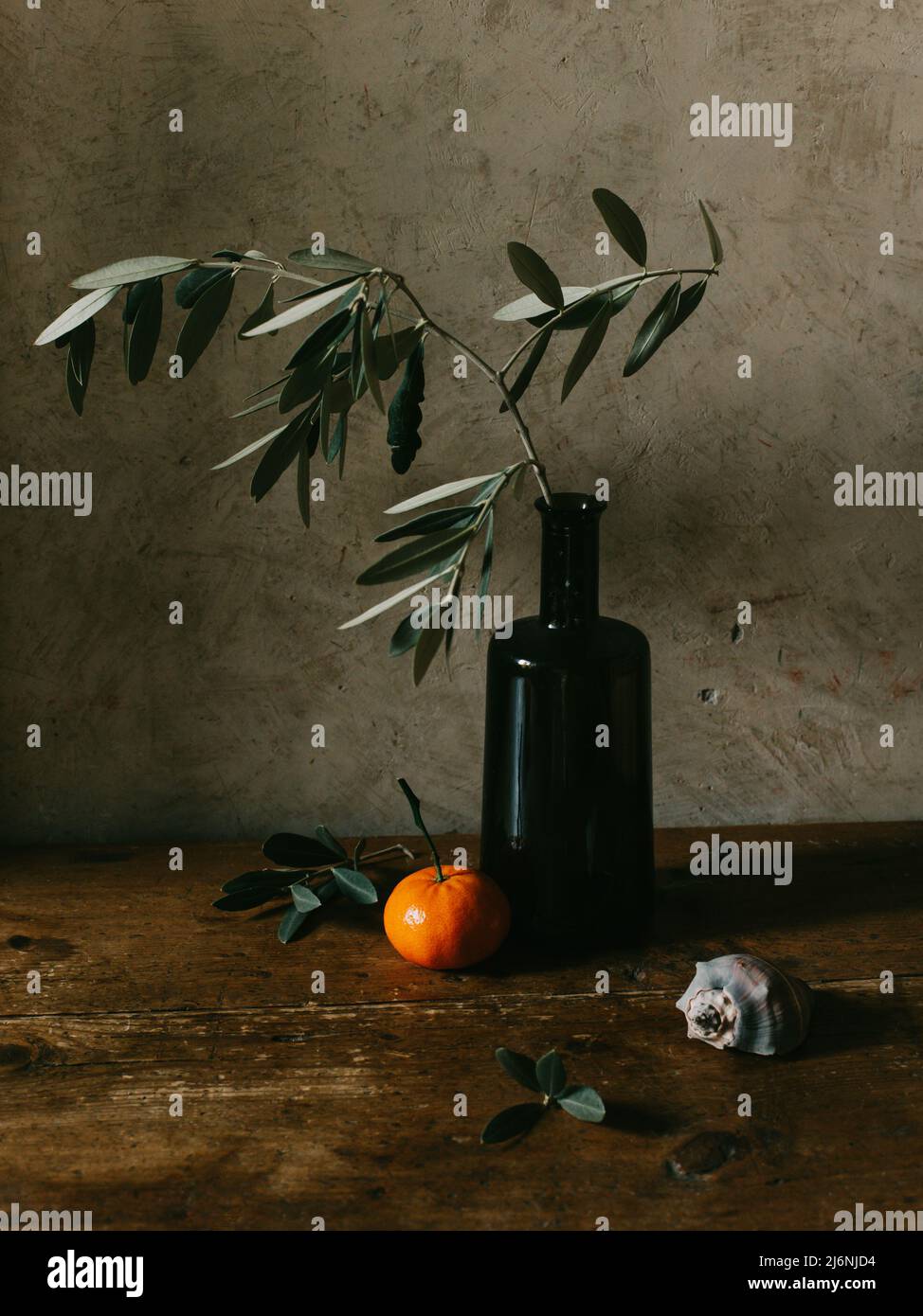 Still life with olive branch and tangerines. Dark rustic background ...