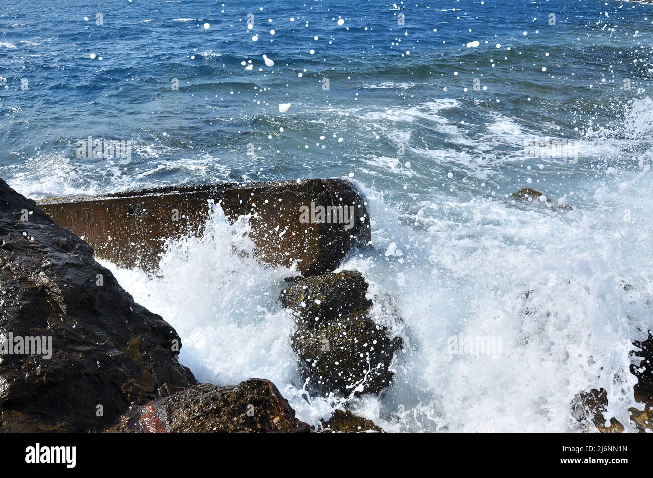 Sea waves are splashing against the hard rocks. Close up of waves ...