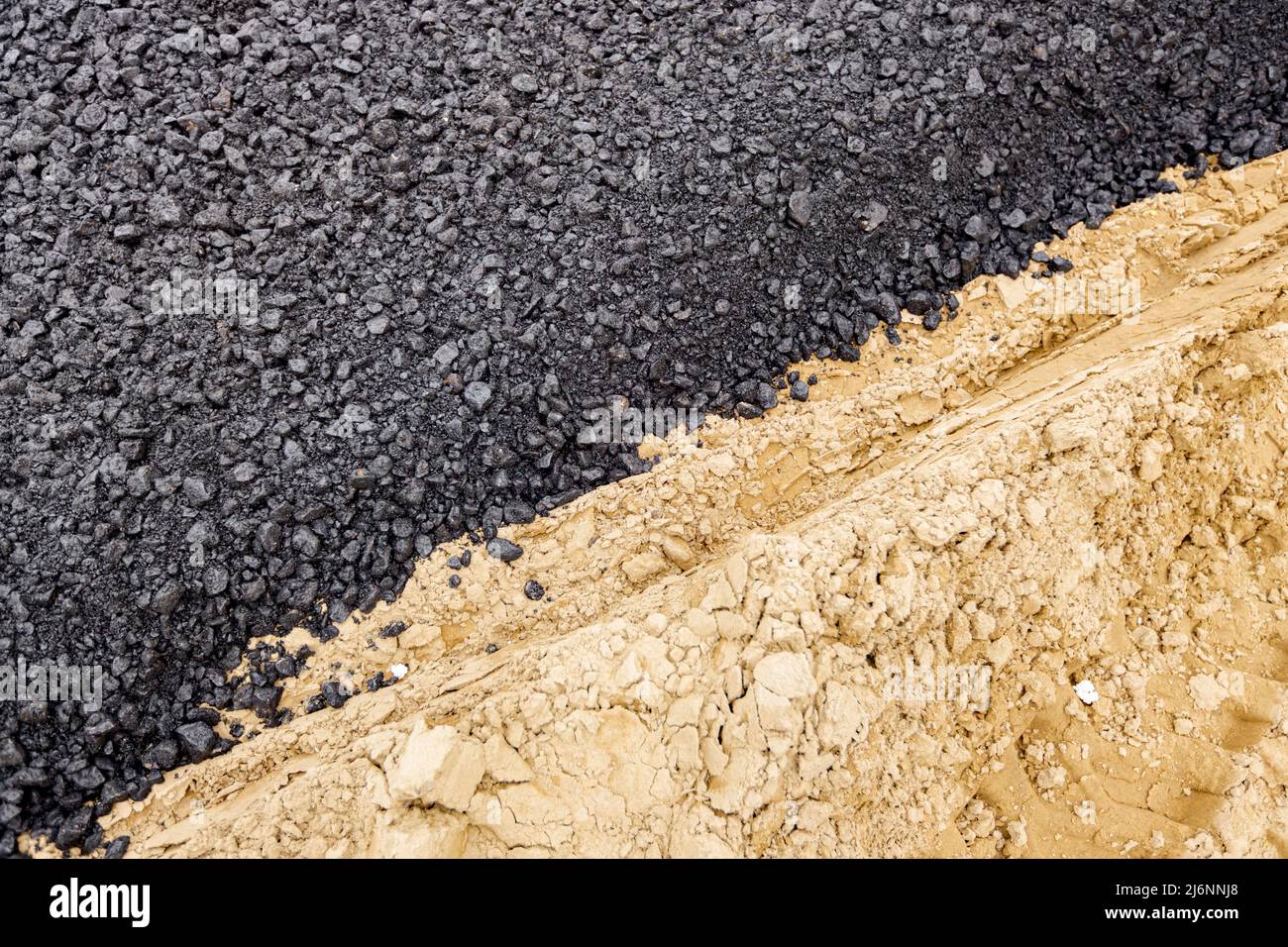 Machine emptied the hot and fresh asphalt into the sand in which are ...